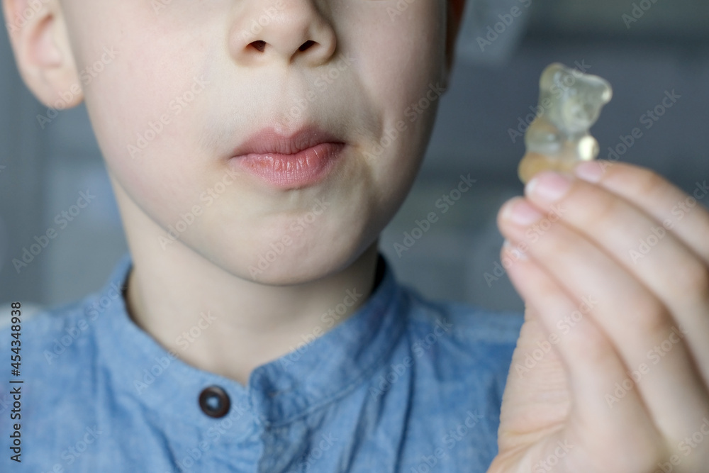 boy, kid holds in hand, wants to eat gelatinous sweets, gummy bear ...
