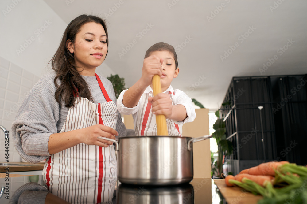 In the kitchen: A single-parent family cooking pasta together. Mother ...
