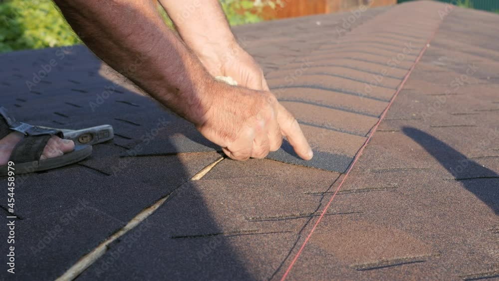 Roofing works. Laying of a soft tile element on the roof ridge and its ...