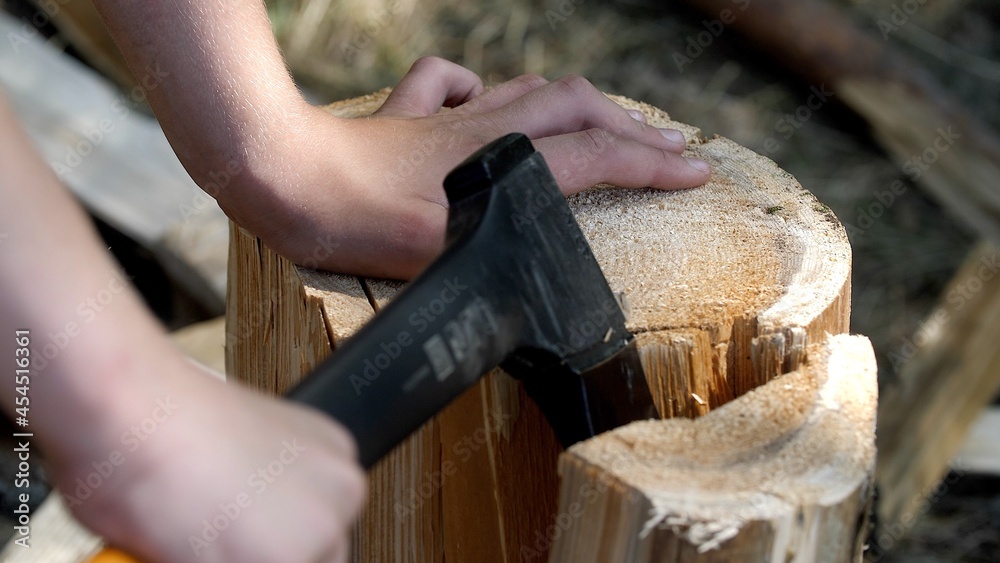Logging wood. Strong male hands chipping off a piece of log with an ax ...