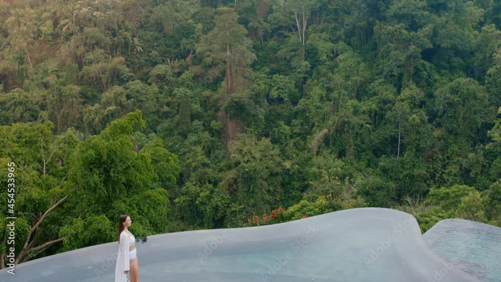 beautiful woman walking by infinity pool wearing bikini enjoying exotic ...