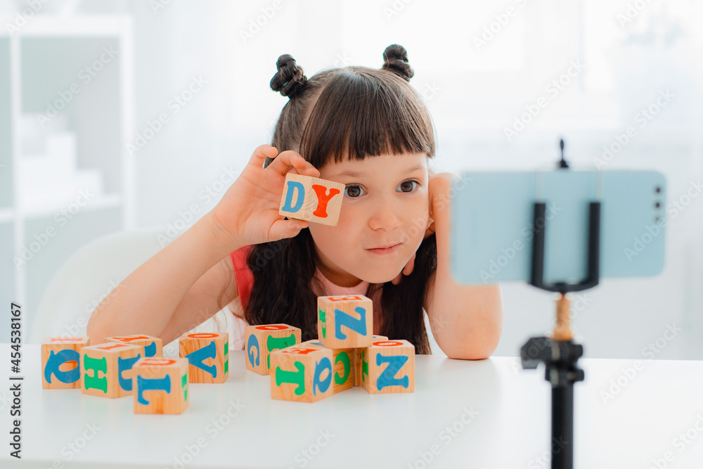 Cute little girl blogger playing with wooden colorful cubes with ...