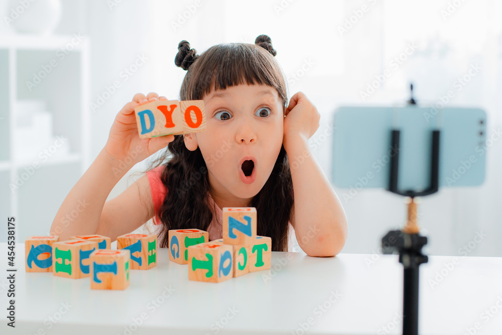 Cute little girl blogger playing with wooden colorful cubes with ...