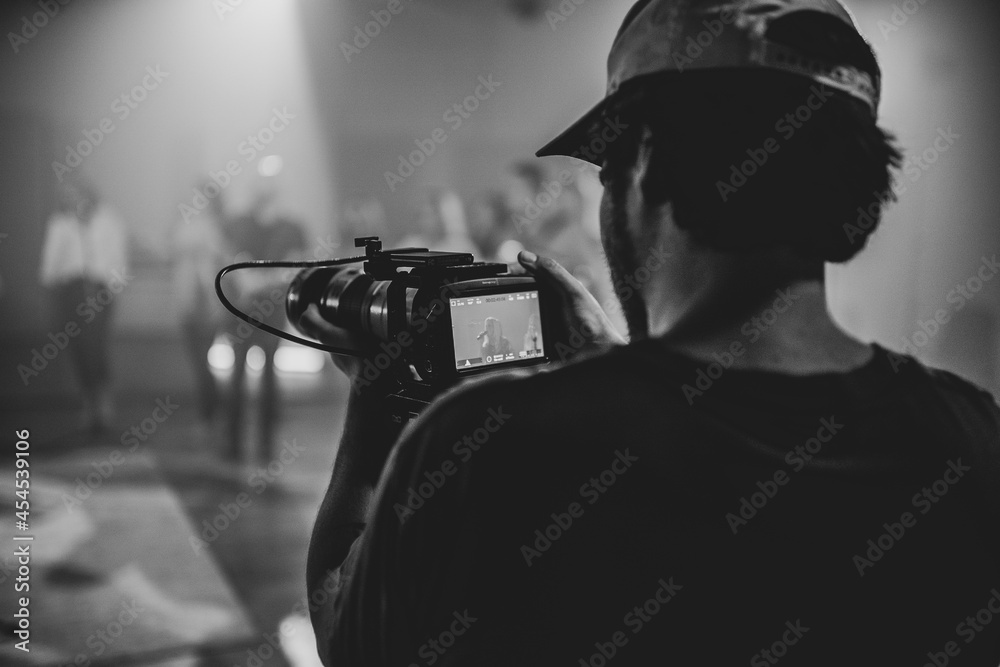 Foto de Grayscale shot of cameraman holding camera on a studio do Stock ...