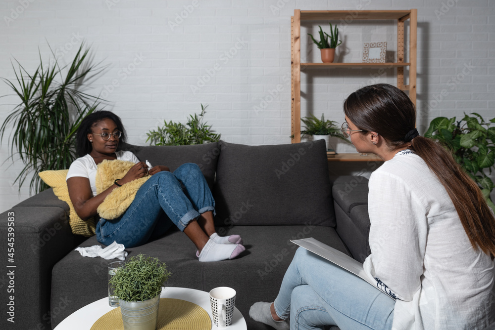 Young black African woman sitting with a psychotherapist in the office ...