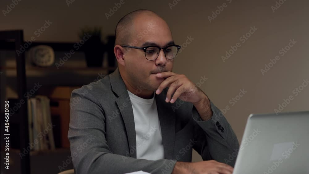 Young asian businessman working with laptop computer in the dark office ...