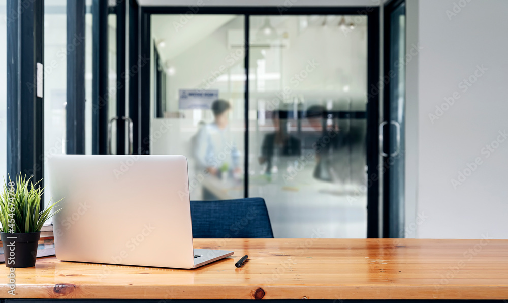 Rear view of laptop computer on wooden table with blur business people ...