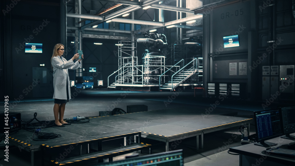 Female Engineer Uses Tablet Computer while Working in an Industial ...