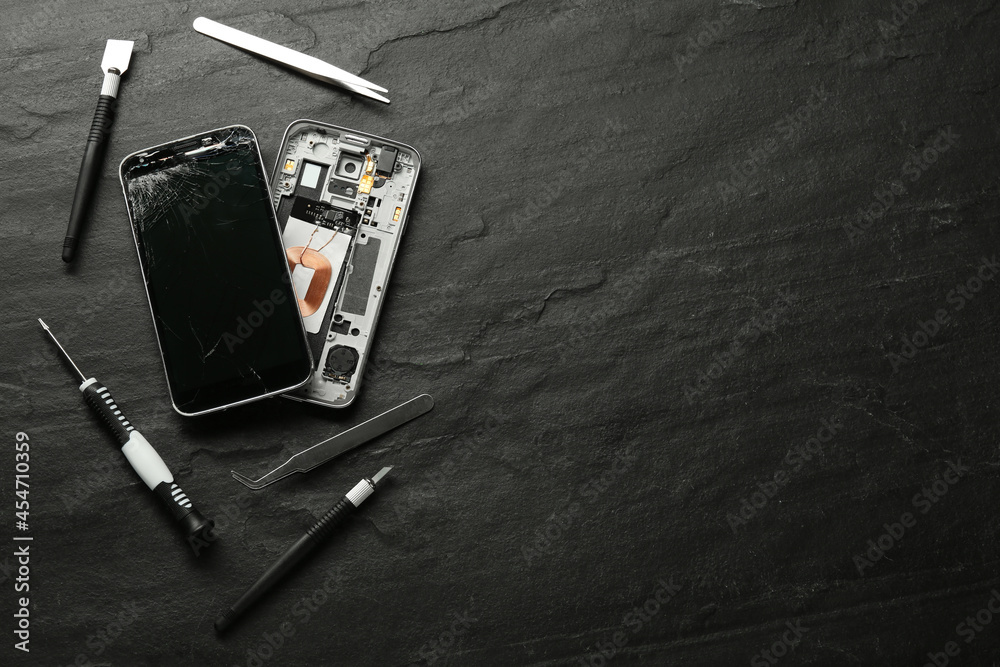 Damaged smartphone and repair tools on black background, flat lay ...