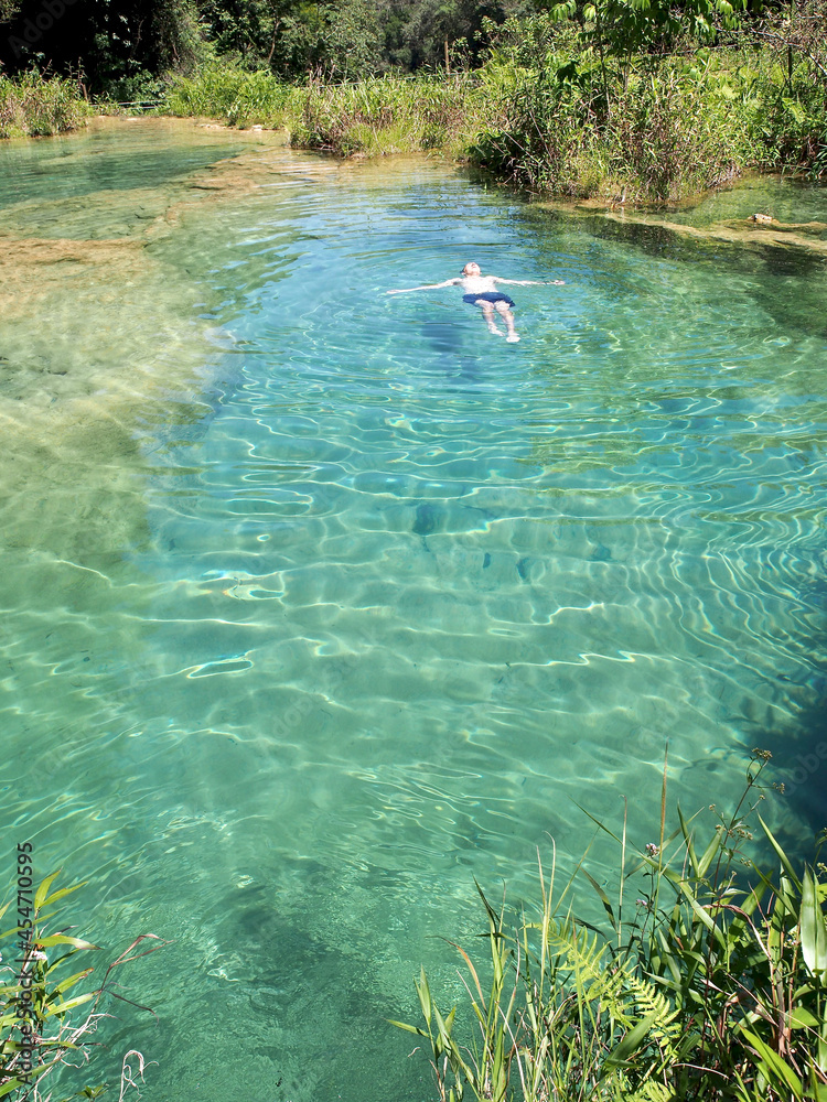 Semuc Champey, Guatemala - Man swimming and floating on back facing up ...