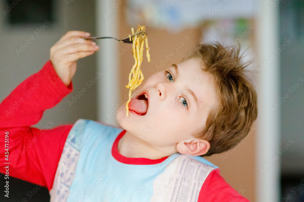 Cute healthy preschool kid boy eats pasta noodles sitting in school or ...