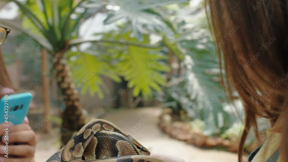 young girl holding snake with friend taking photo using smartphone ...
