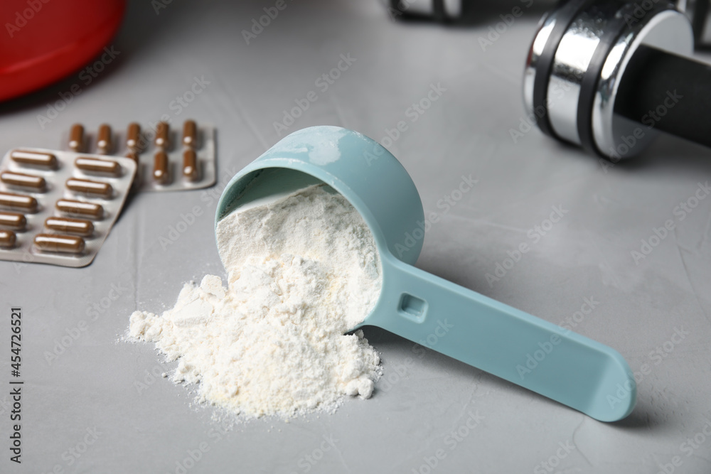 Measuring scoop of amino acids powder on light grey table Stock Photo ...