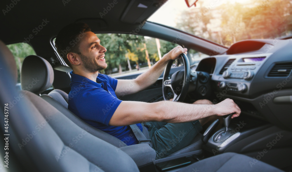 Close up photo of young handsome successful man is driving his modern ...