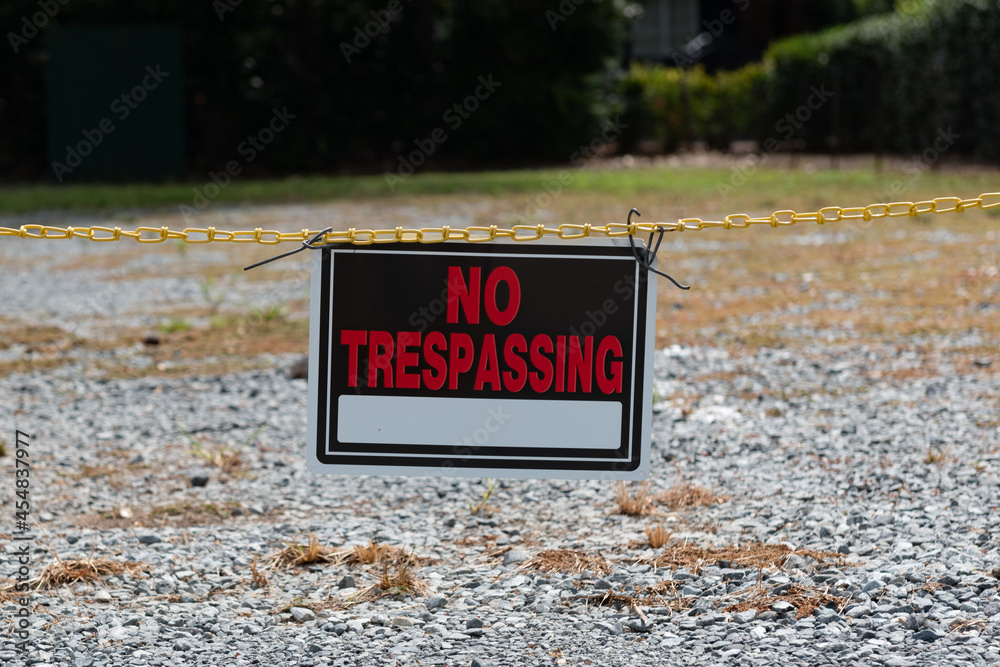 No trespassing sign hanging on a chain at the entrance to an abandoned ...