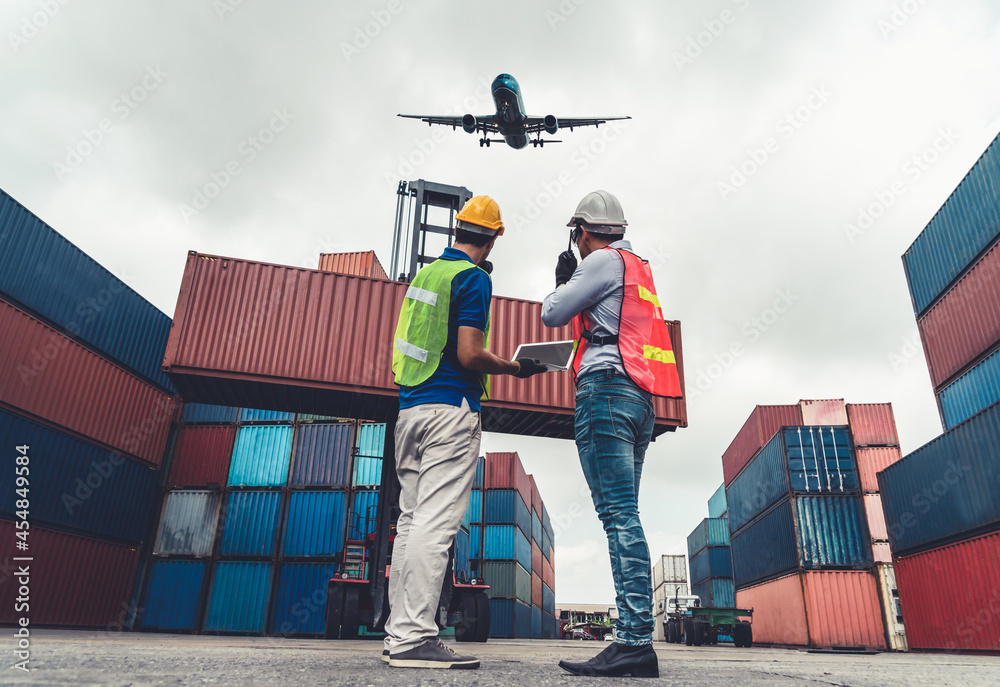 Industrial worker works with co-worker at overseas shipping container ...