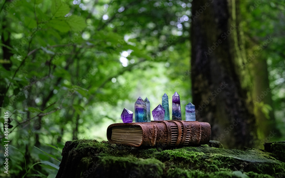 witch book and quartz minerals on natural forest background. Healing ...
