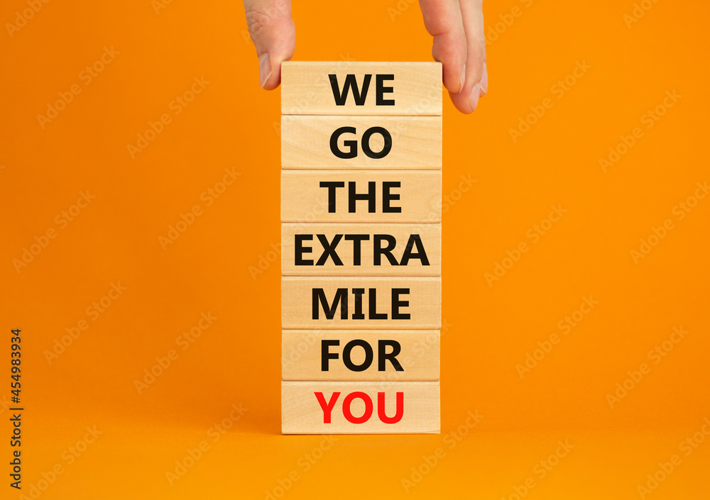 Go the extra mile symbol. Wooden blocks with words 'We go the extra ...
