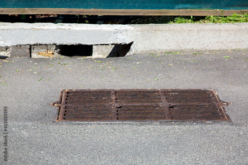 drainage grate on a rectangular manhole on an asphalt road with a storm ...
