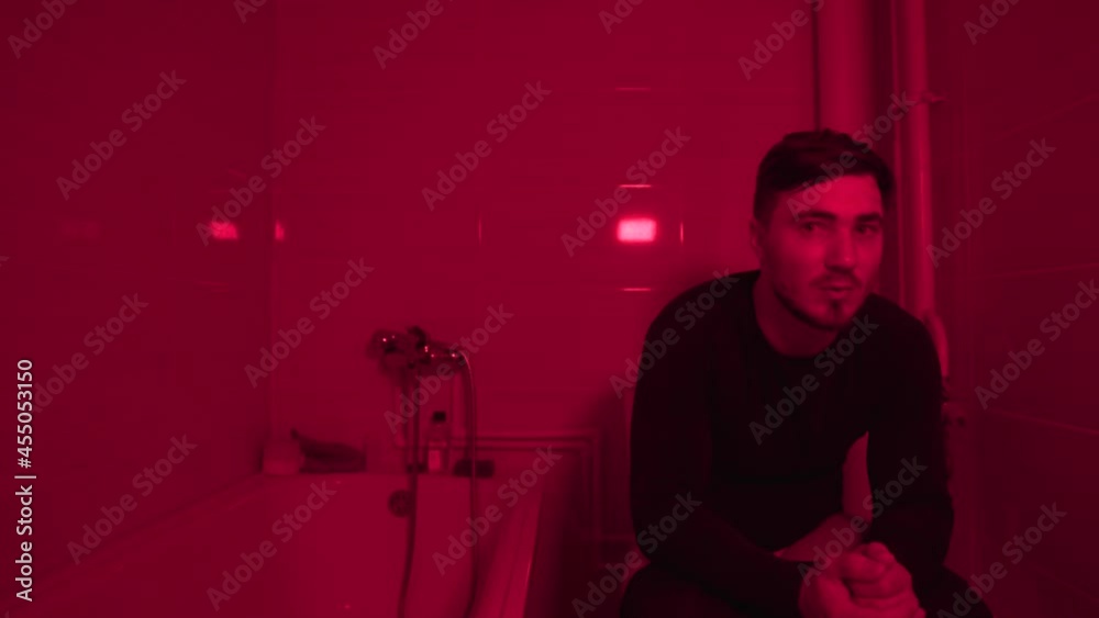 Cheerful Man Sits on the Toilet in a Nightclub, Shakes His Head in the ...
