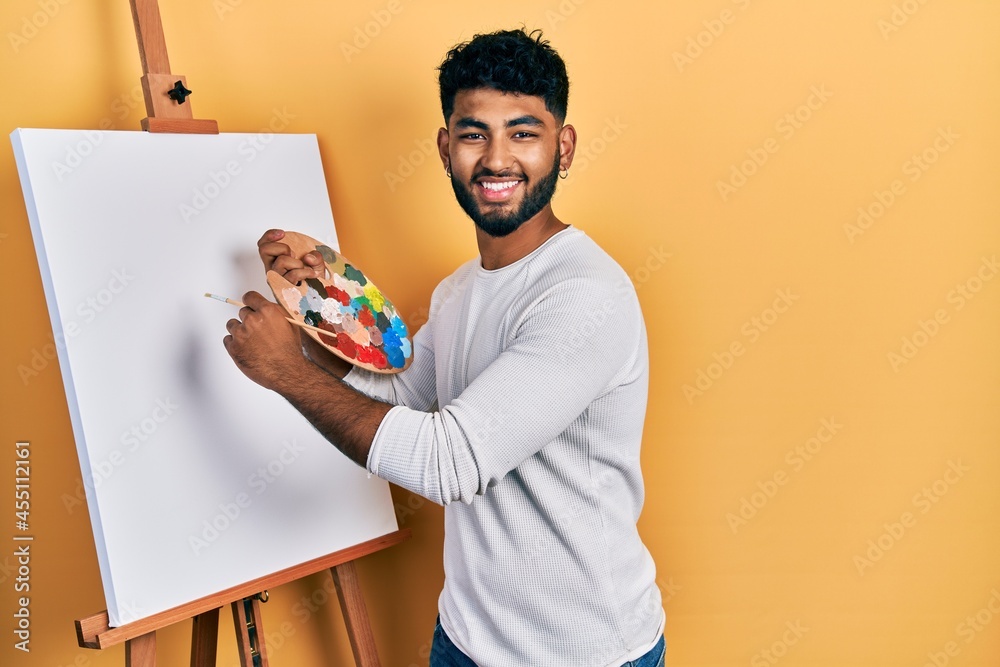 Arab man with beard standing drawing with palette by painter easel ...
