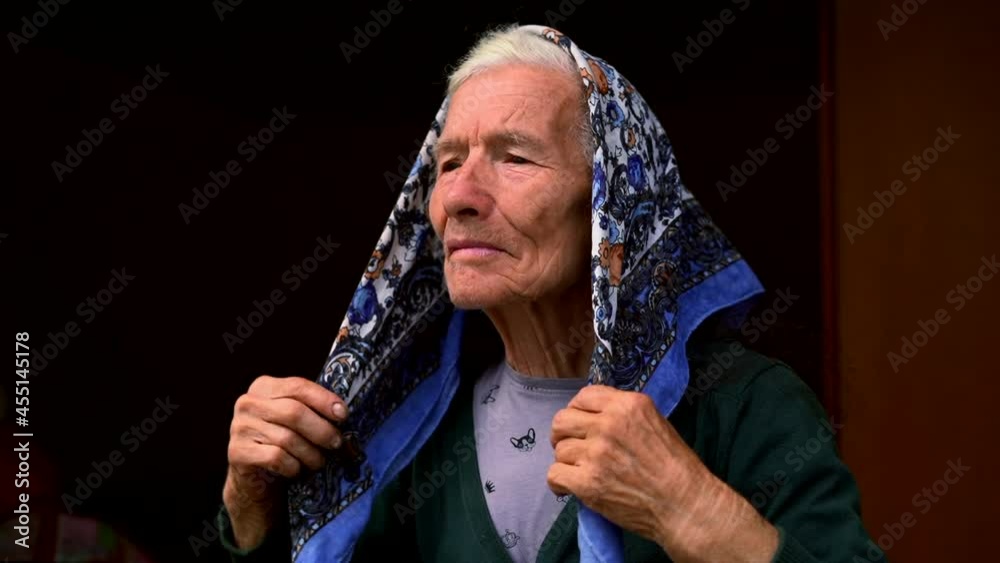 Old Country Woman With Gray Hair And A Wrinkled Face Is Tying A Scarf