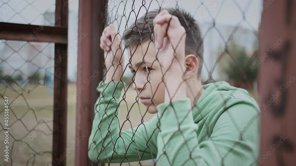 Vídeo do Stock: cinematic refugee sad boy stands alone head bowed near ...