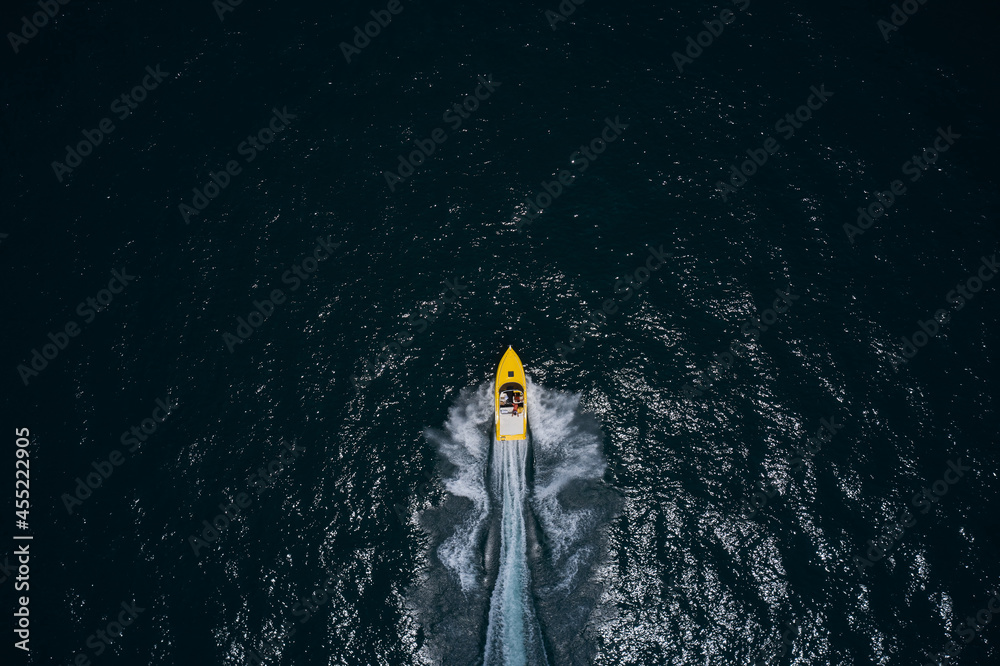 Large yellow boat moving on dark water. Speedboat on dark blue water ...