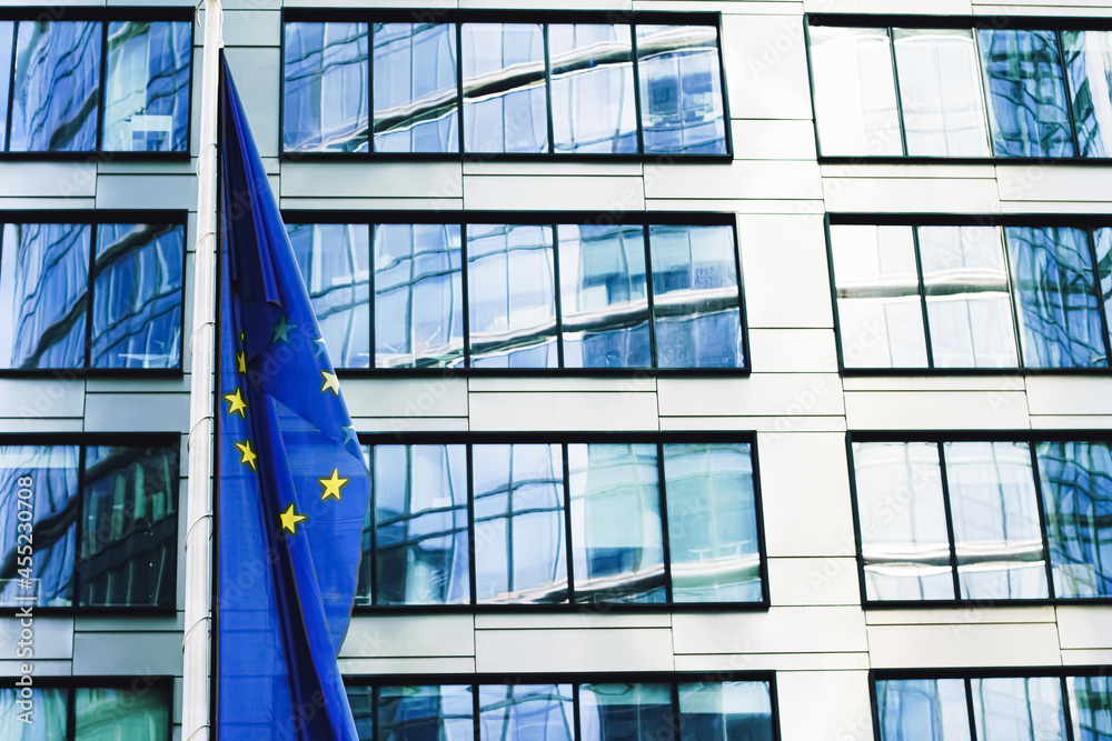 European Union flag waving in front of modern corporate office building ...