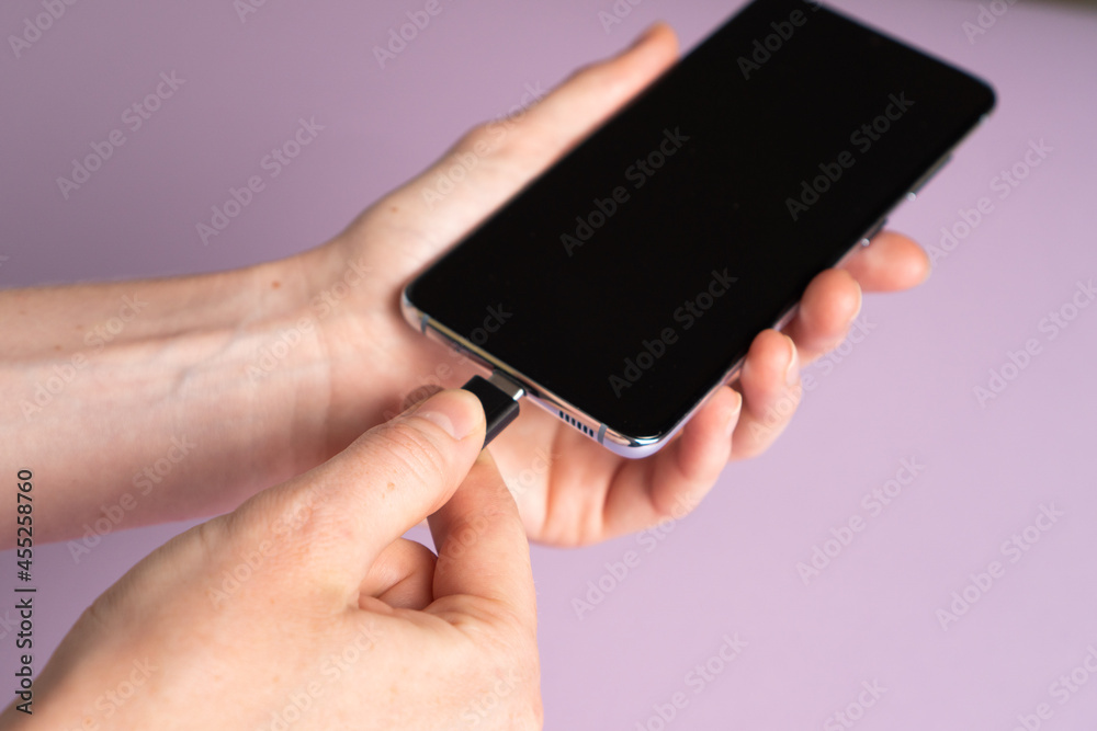 Phone in a hand. Charging smartphone. Plugin Type-C cord into the phone ...