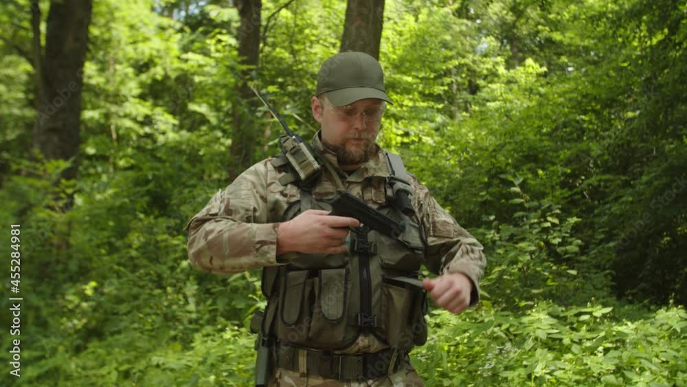 Serviceman in combat gear pulling out weapon from tactical vest ...