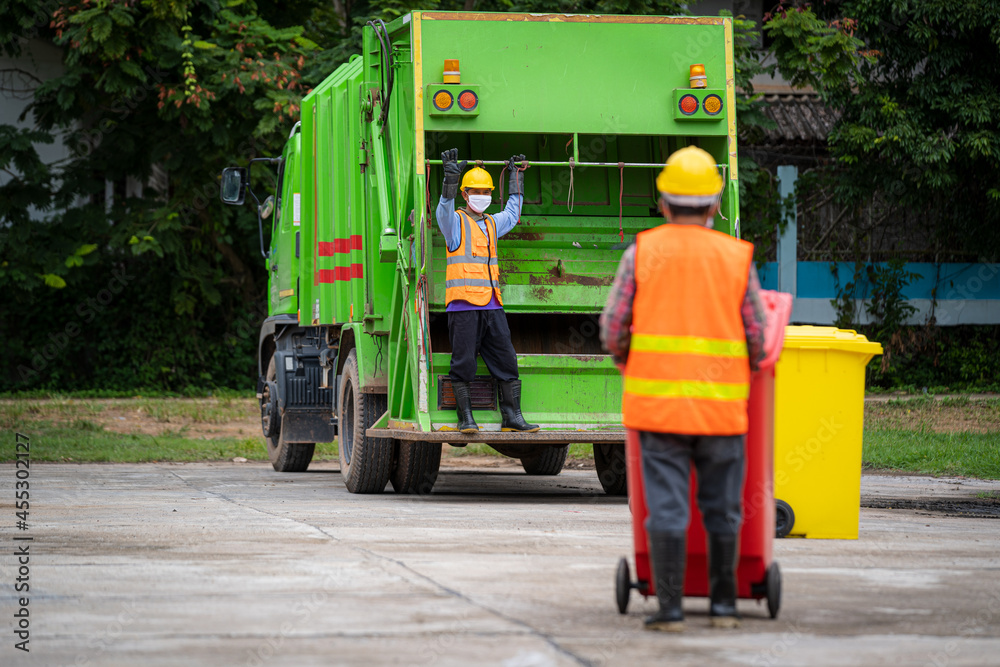 Rubbish cleaner man working with green garbage truck loading waste and ...