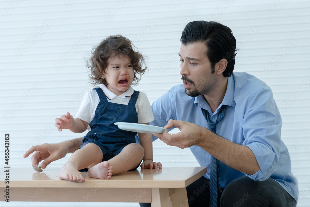 Little Caucasian kid girl with curly hair is sitting on table crying ...