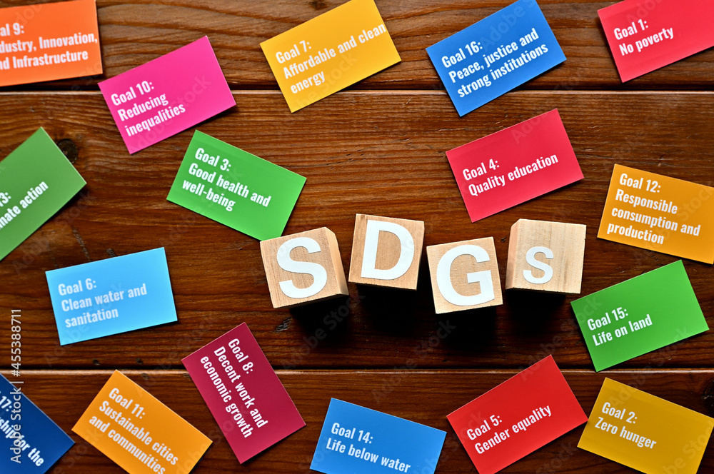 On a wood board, wooden word cubes are arranged in the letters SDGs. It ...