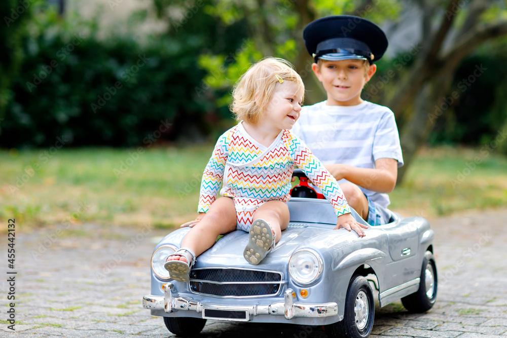 Two happy children playing with big old toy car in summer garden ...