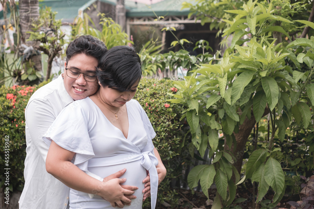 A Filipino couple embrace each other, feeling the baby bump on the wife ...