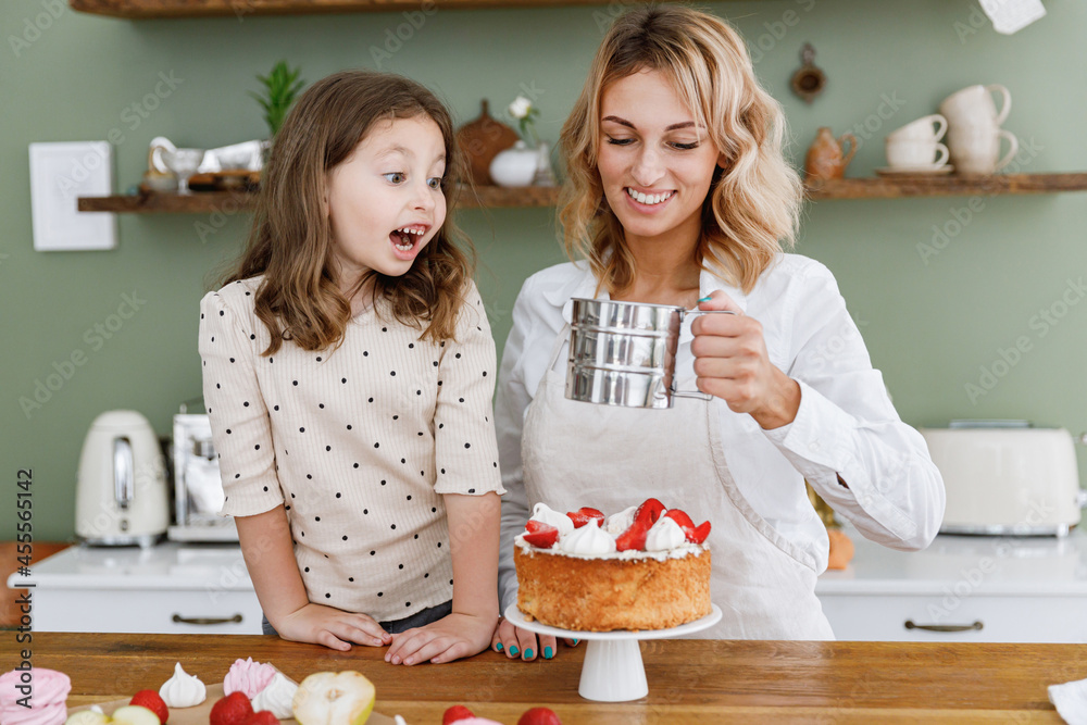 Happy cute chef cook baker mom woman in white shirt work with baby girl ...