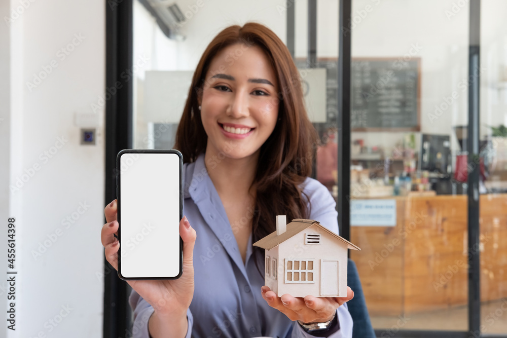 Real estate agent showing house model and mobile phone with blank white ...