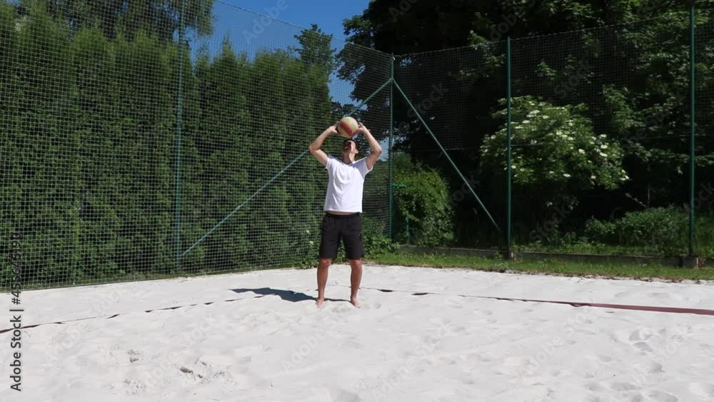 Young volleyball player in a white t-shirt and black shorts shows ...