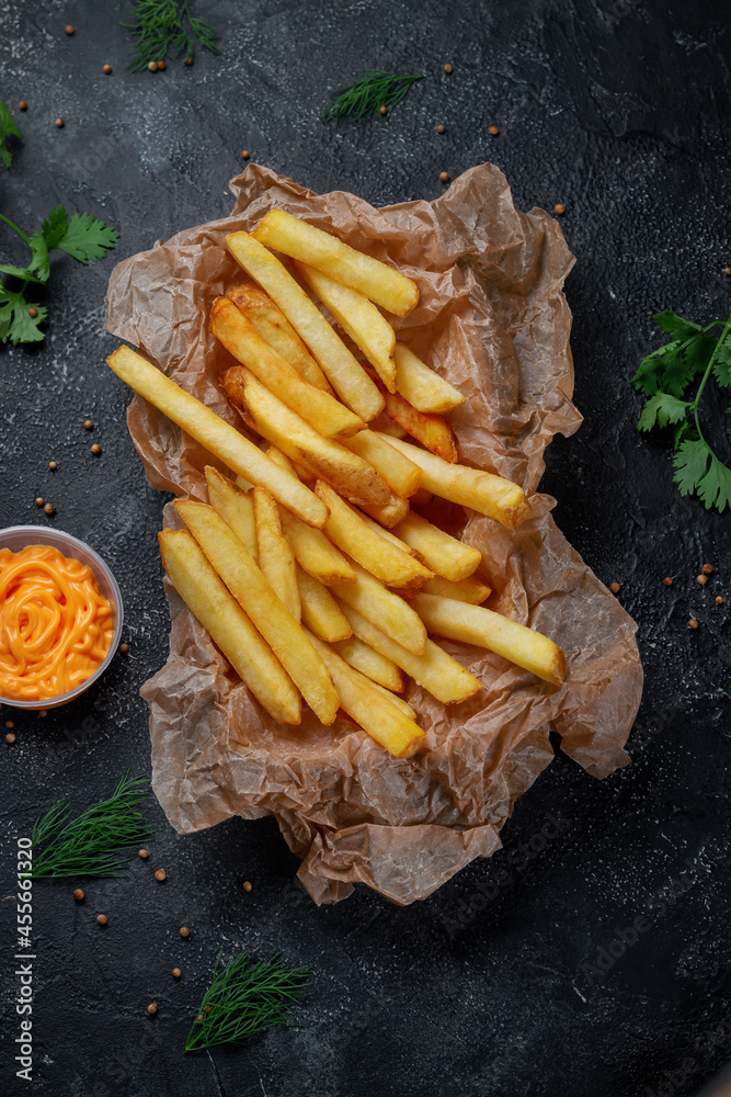 Crispy delicious french fries on a dark stone background with cheese ...