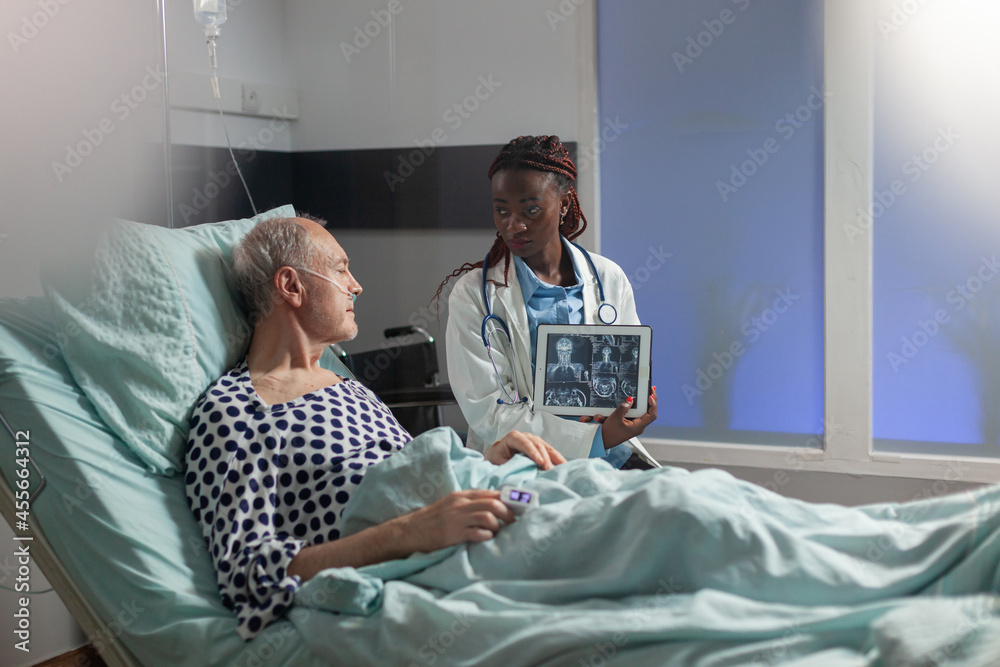African american doctor sitting next to senior man explaining body ...