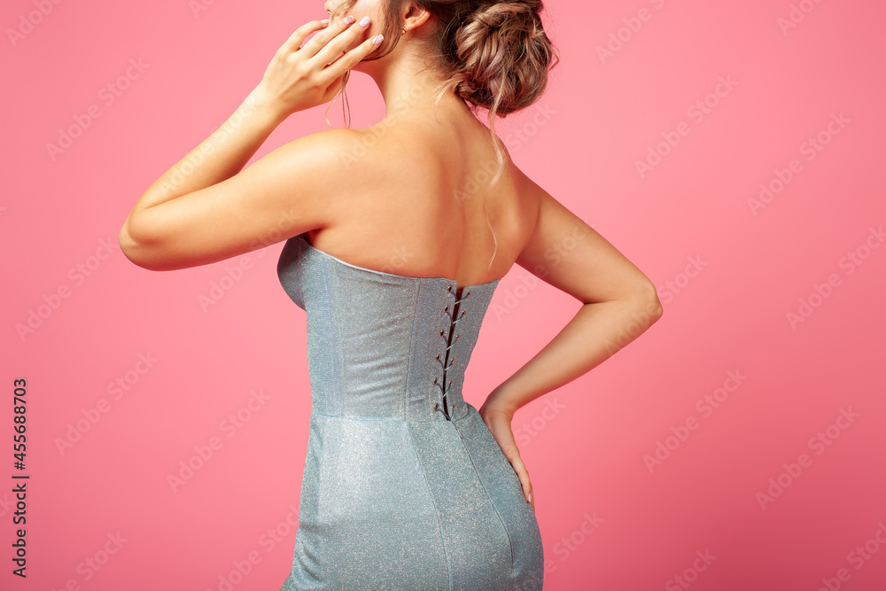 back view closeup on back of young woman in blue shiny tight dress with ...