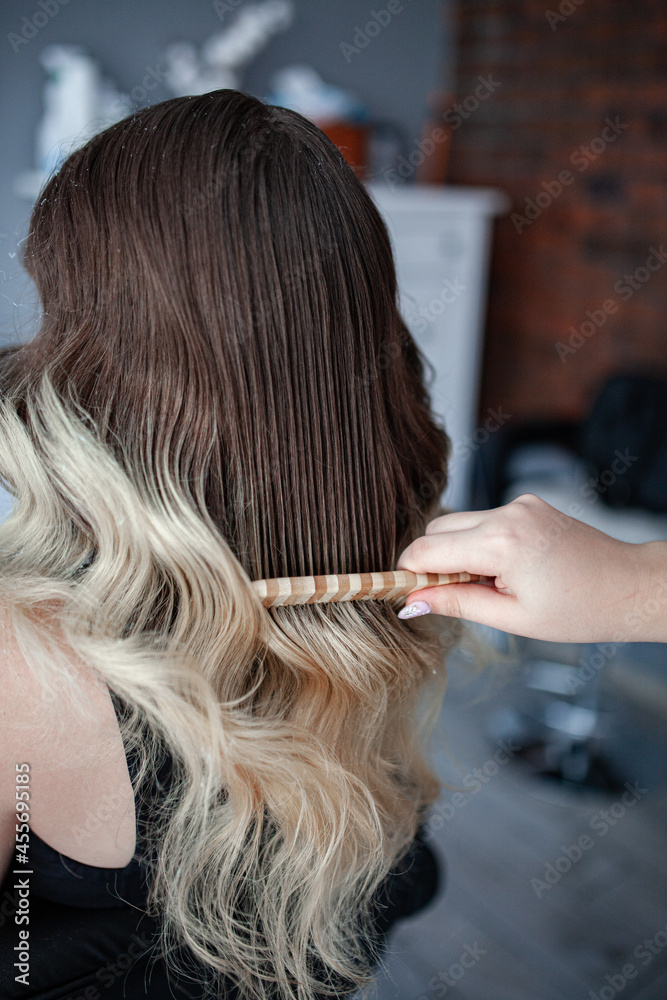 stylist hairdresser makes a hairstyle for a girl in his beauty salon ...