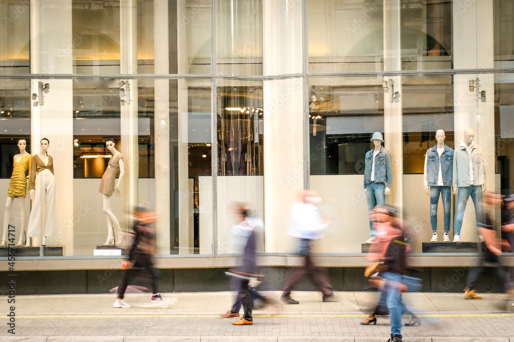 Motion blurred people walking past retail shop window on London high ...