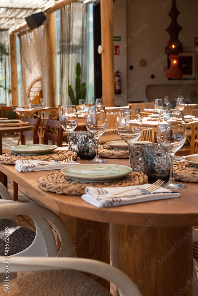 Mesa de restaurante turístico en la playa con copas, vasos, platos y ...