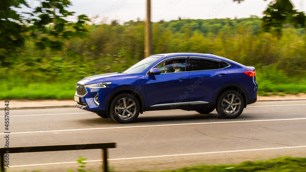 Haval F7x five door SUV is driving at high speed on country road. Overspeed out of city concept ...