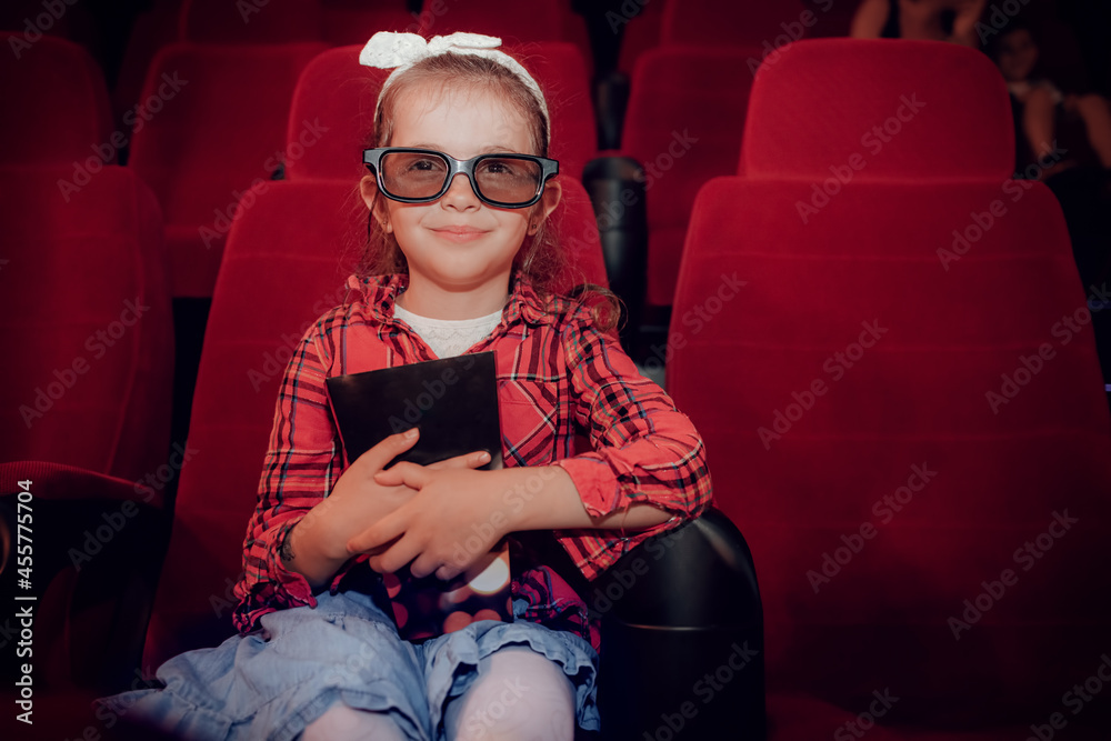 Little girl watching cartoon 3D movie in cinema and eating popcorn Stock Photo | Adobe Stock