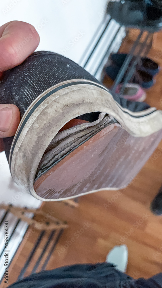 sad generic rugged sneakers, shoes with a hole on the sole. close up of ...