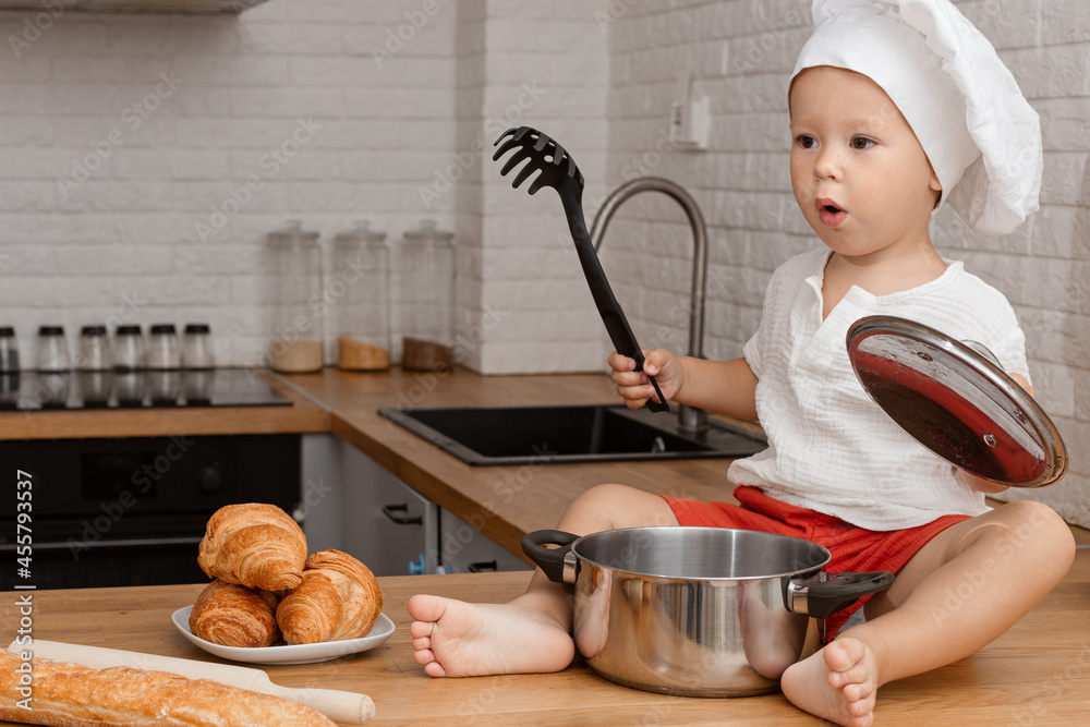 kid in the kitchen, a little boy in a chef's hat with a pole and a pot ...