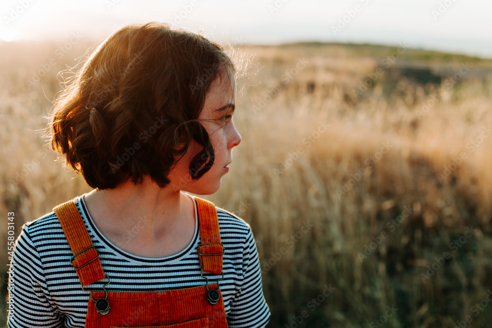 Child looking back profile shot in field. Stock Photo | Adobe Stock